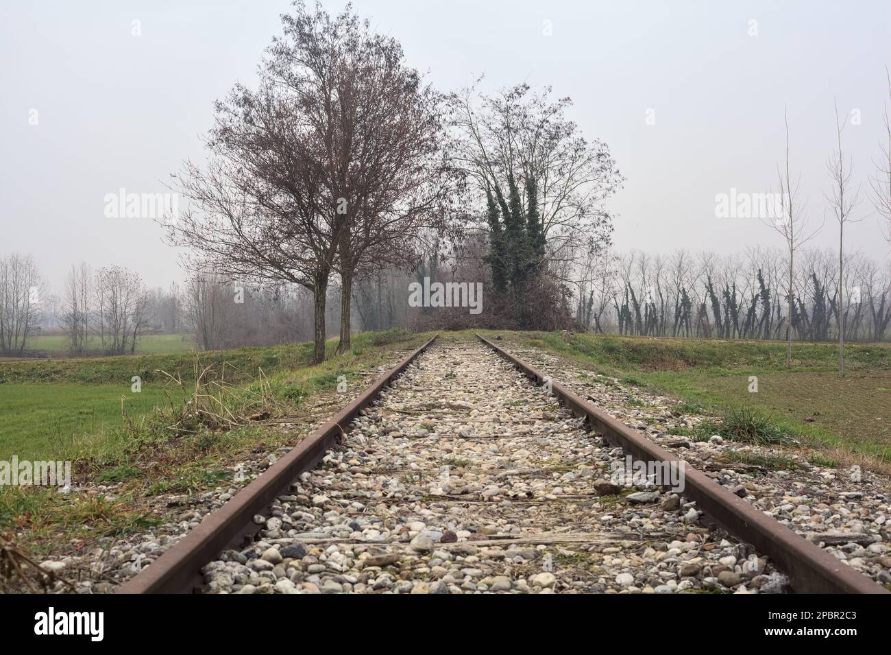 Abandoned railroad track on an embankment between fields on a cloudy ...