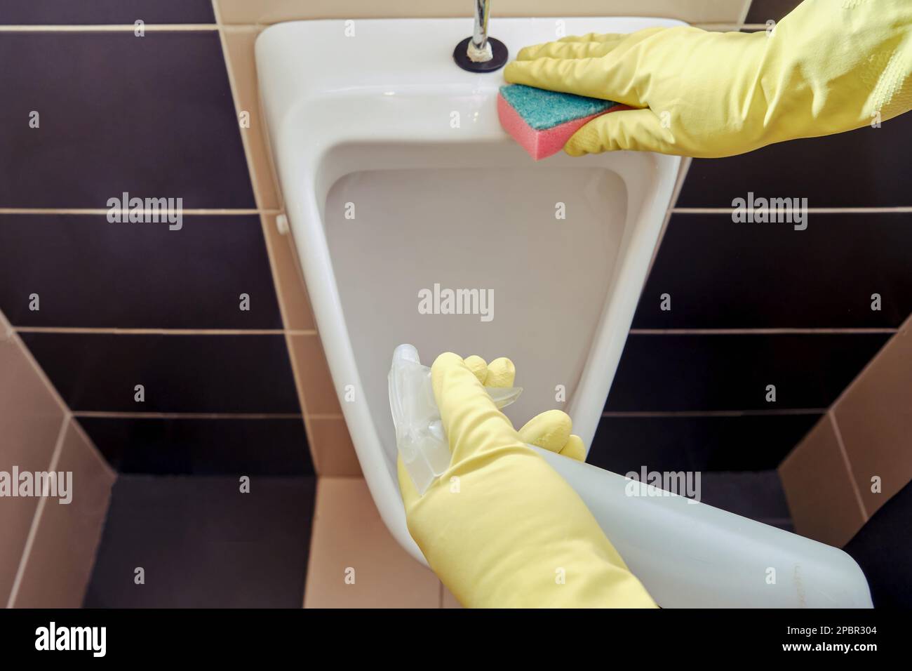 Cleaning in a public toilet cafe, a man hand in yellow gloves wipes the ...