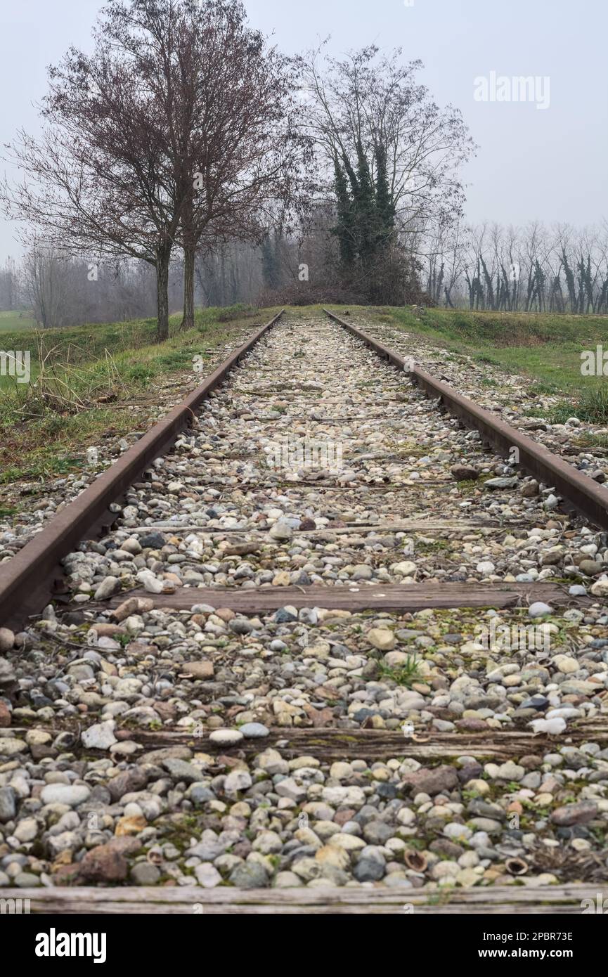 Abandoned railroad track on an embankment between fields on a cloudy ...