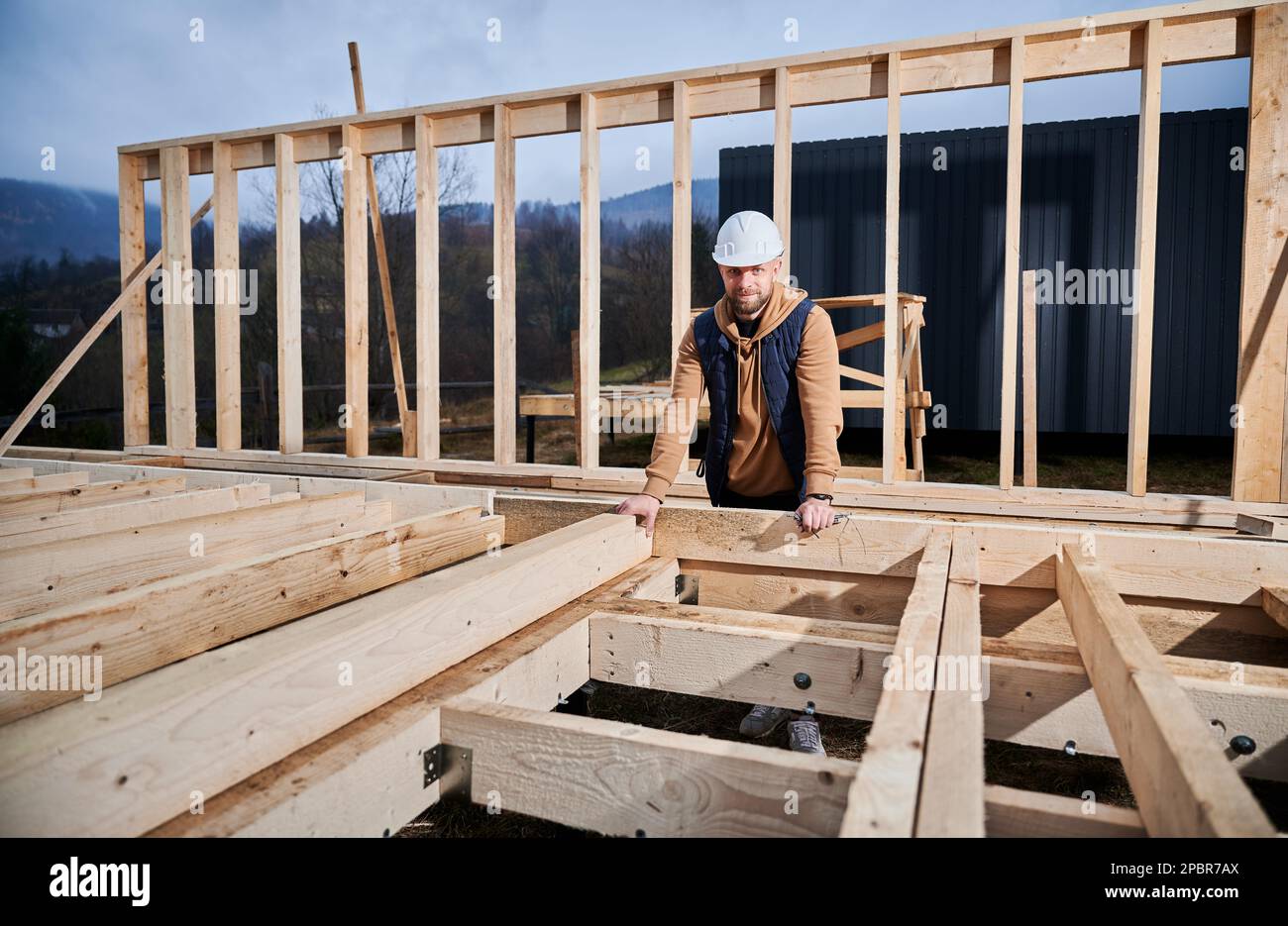 Male developer building wooden frame house. Portrait of man standing on construction site in ...