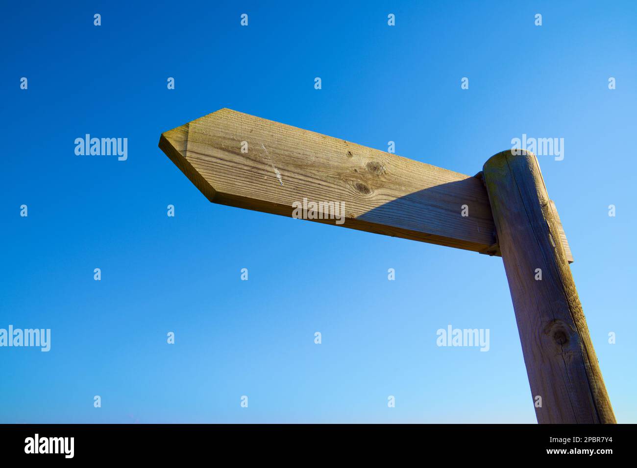 Wooden arrow on a pole indicating direction and clear blue sky Stock ...