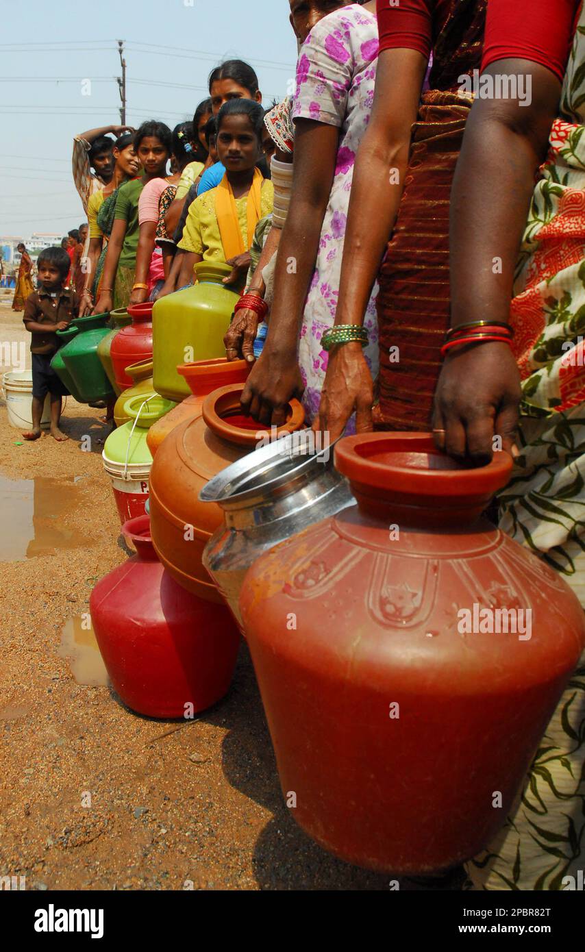 People stand in a queue for water at a slum area in Hyderabad, India ...