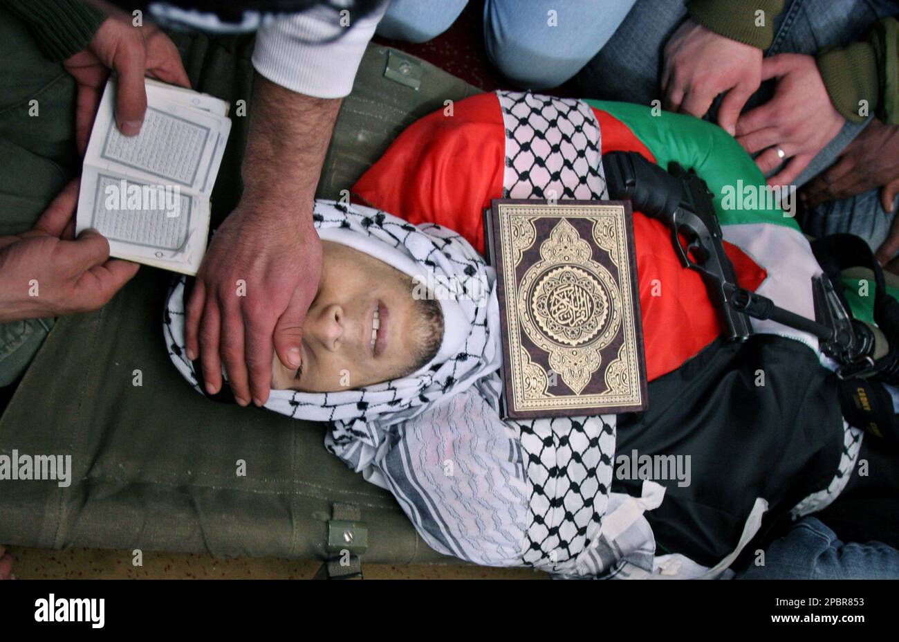 A Quran, the Muslim holy book and a rifle are placed on the body of ...