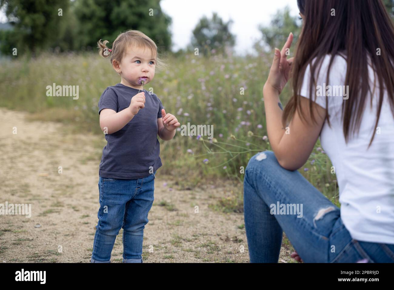Little girl learning numbers from her mother standing in a rural path ...