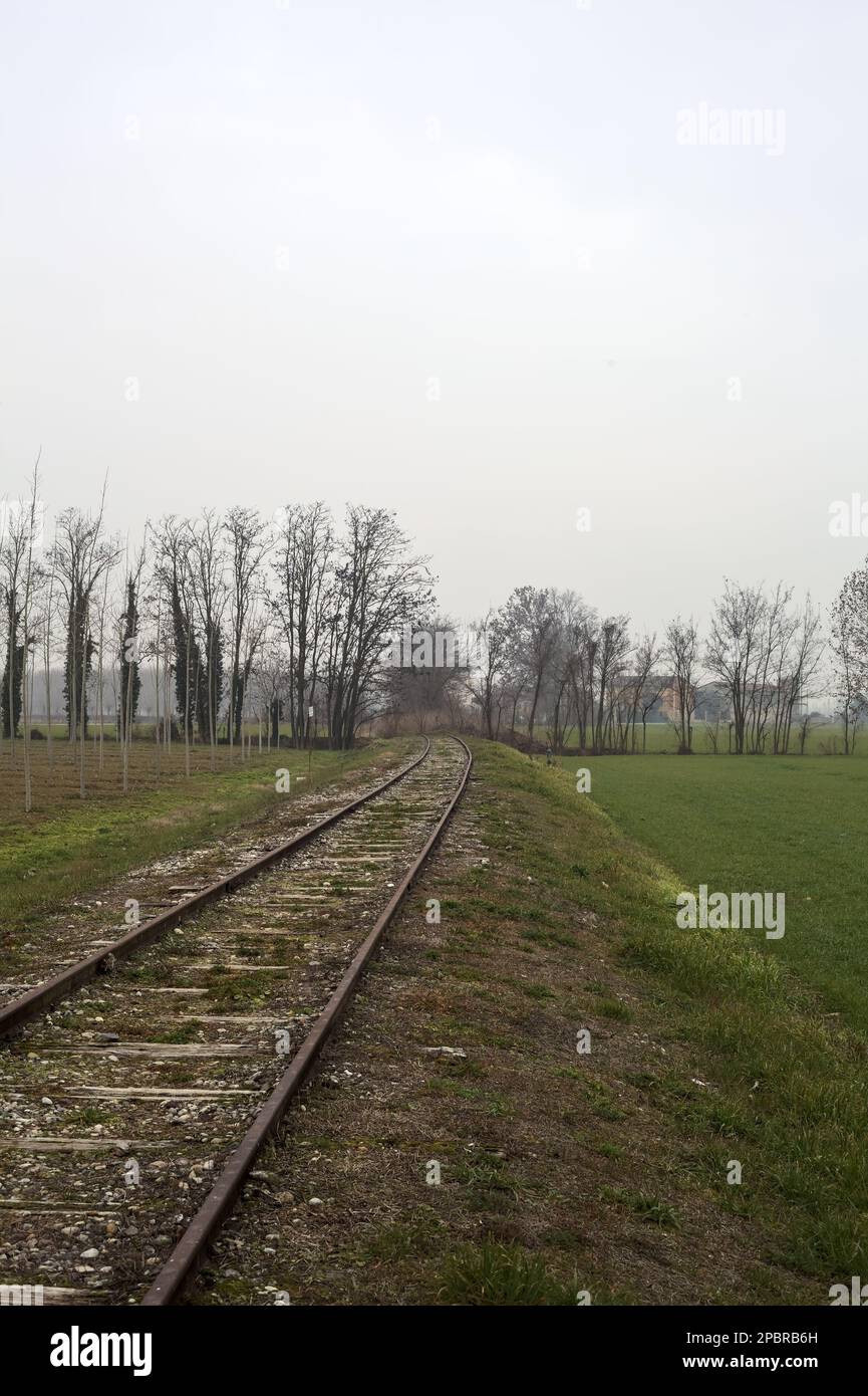 Abandoned railroad track on an embankment between fields on a cloudy ...