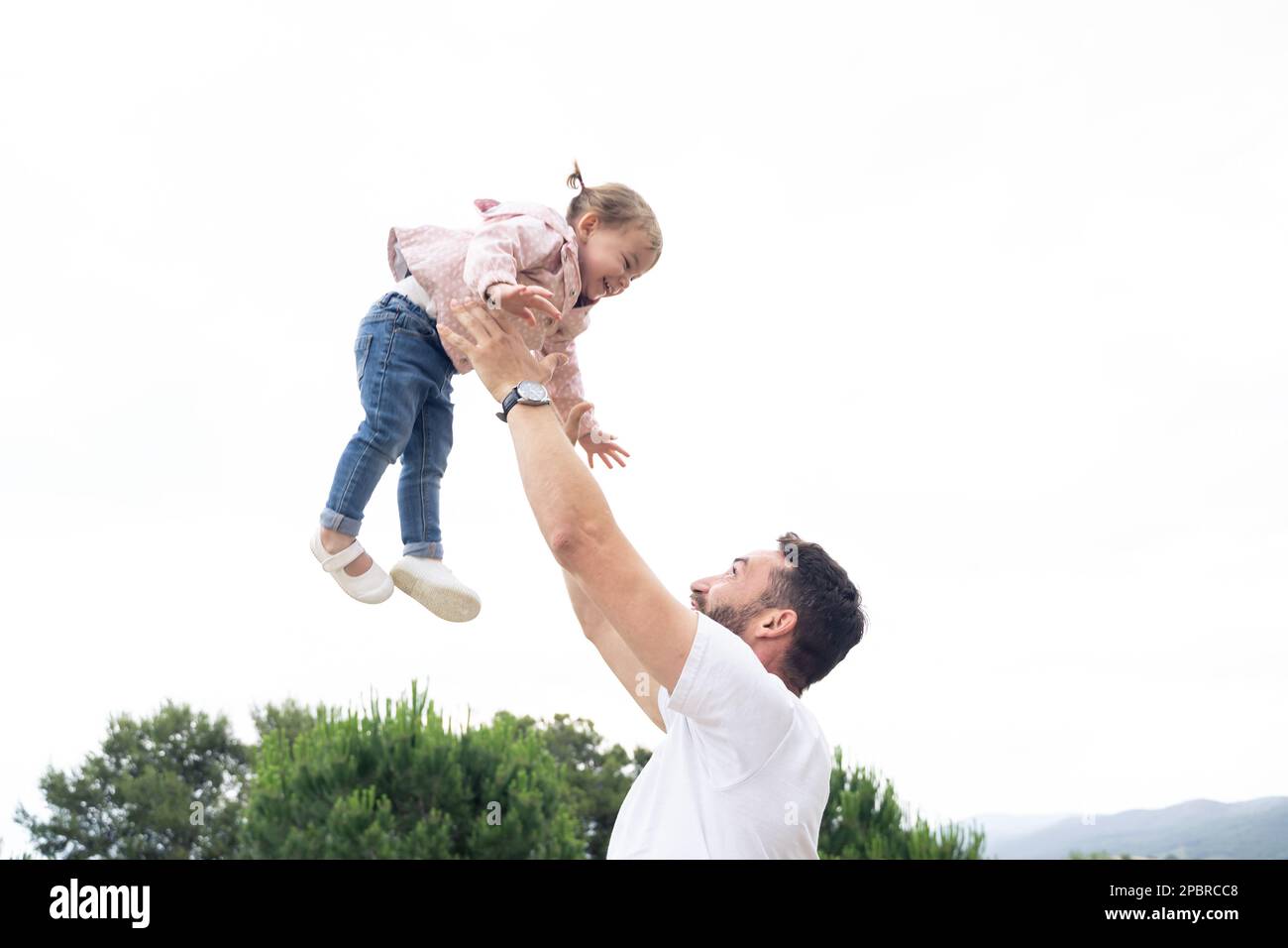 Portrait of a playful dad lifting on the air her little daughter Stock ...