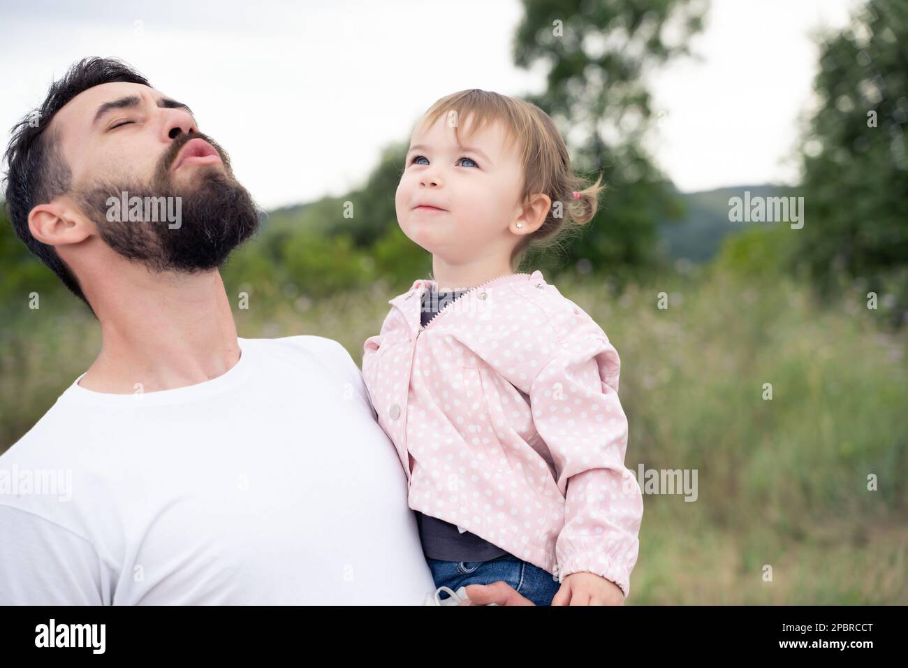 Playful father teaching how to howl to a little girl in a rural path ...