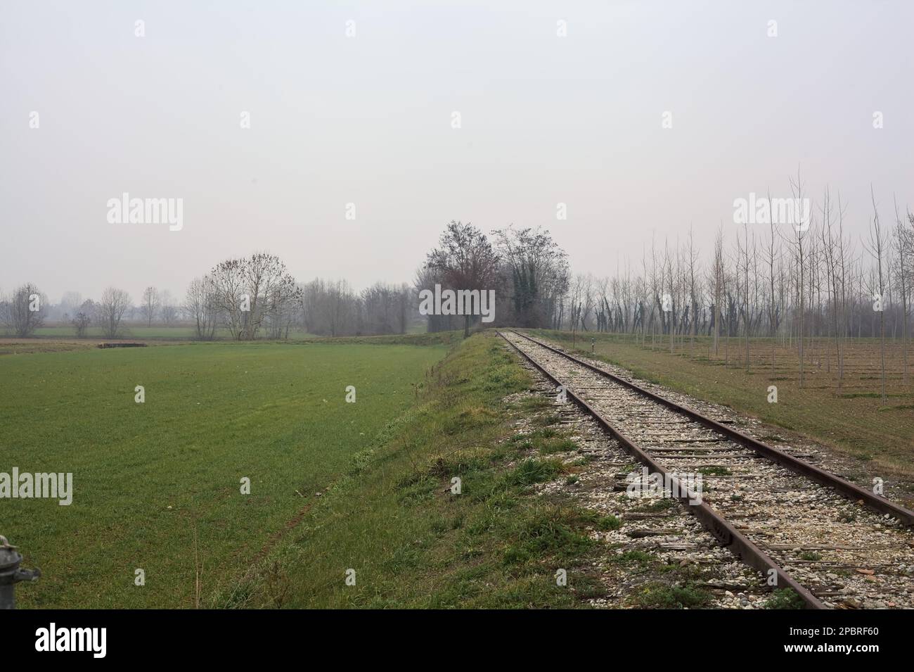 Abandoned railroad track on an embankment between fields on a cloudy ...