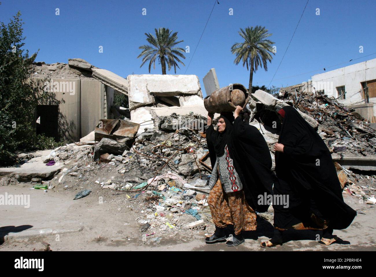 Iraqi women pass a house destroyed during air campaign at early stages ...