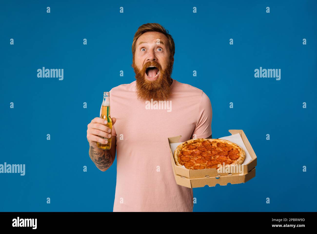 Portrait of excited ginger bearded man screaming while holding beer and ...
