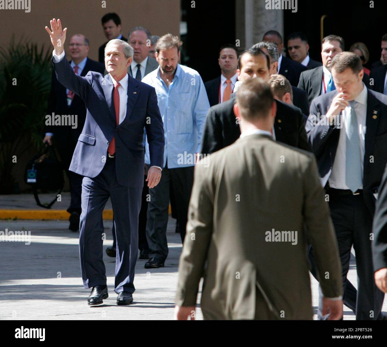 U.S. President George W. Bush waves as he crosses the street to a news ...