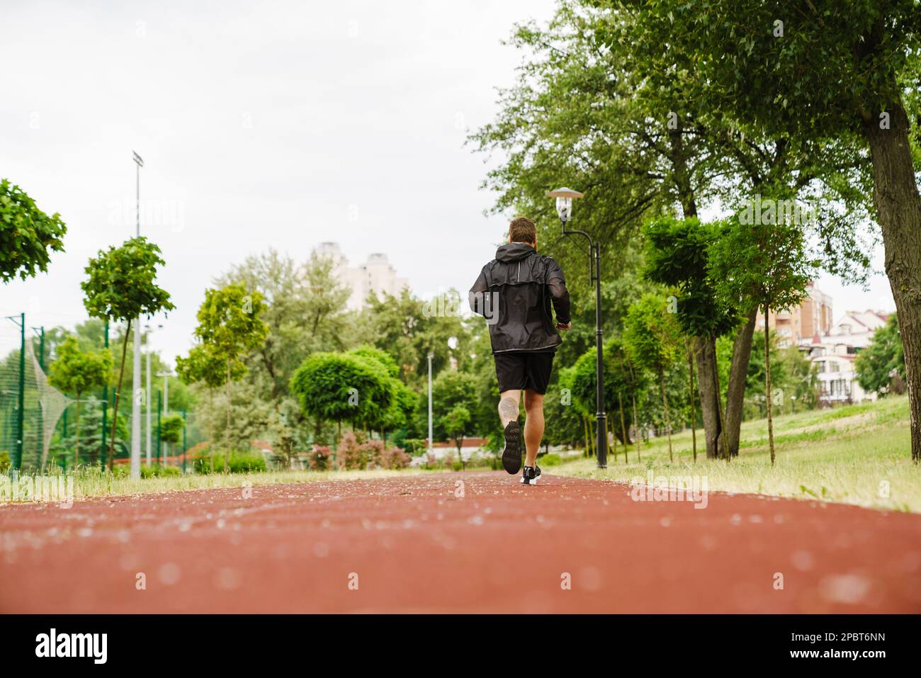 Back view of man running in black sport suit on track outdoors Stock ...