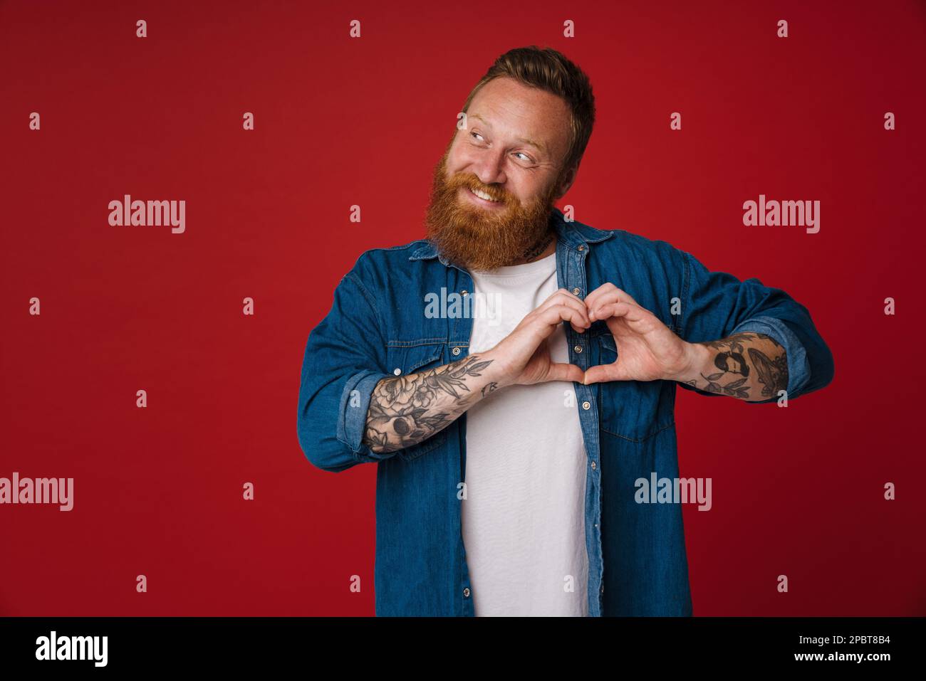 Adult redhead bearded tattooed smiling man in t-shirt doing heart ...