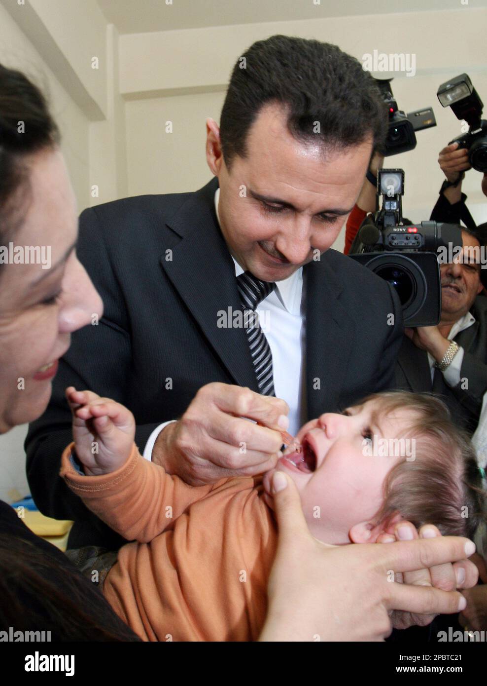 Syrian President Bashar Assad, a former eye doctor, gives a Syrian child an oral vaccination on ...