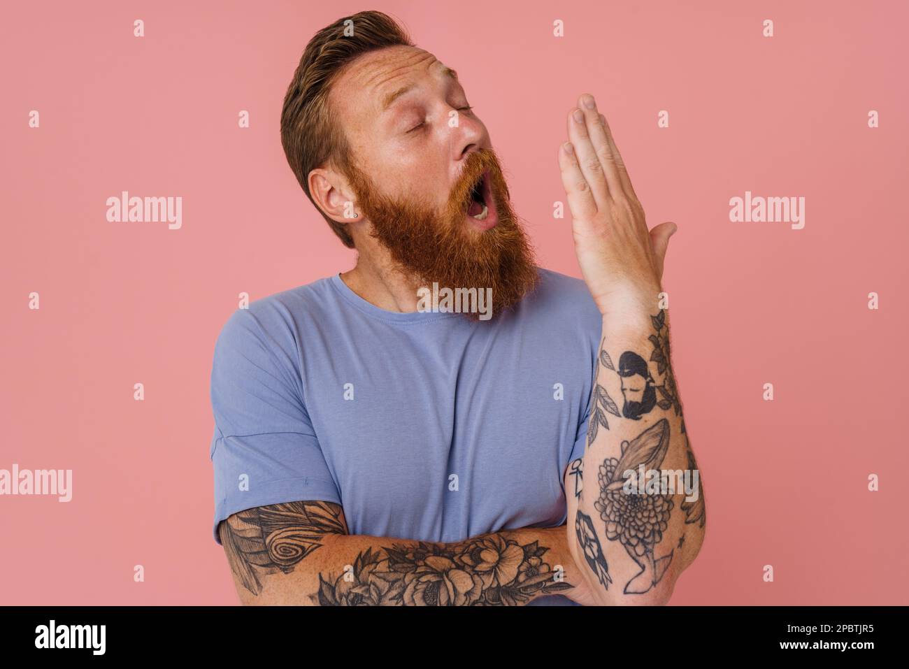 Ginger perplexed man with beard yawning and covering his mouth isolated ...