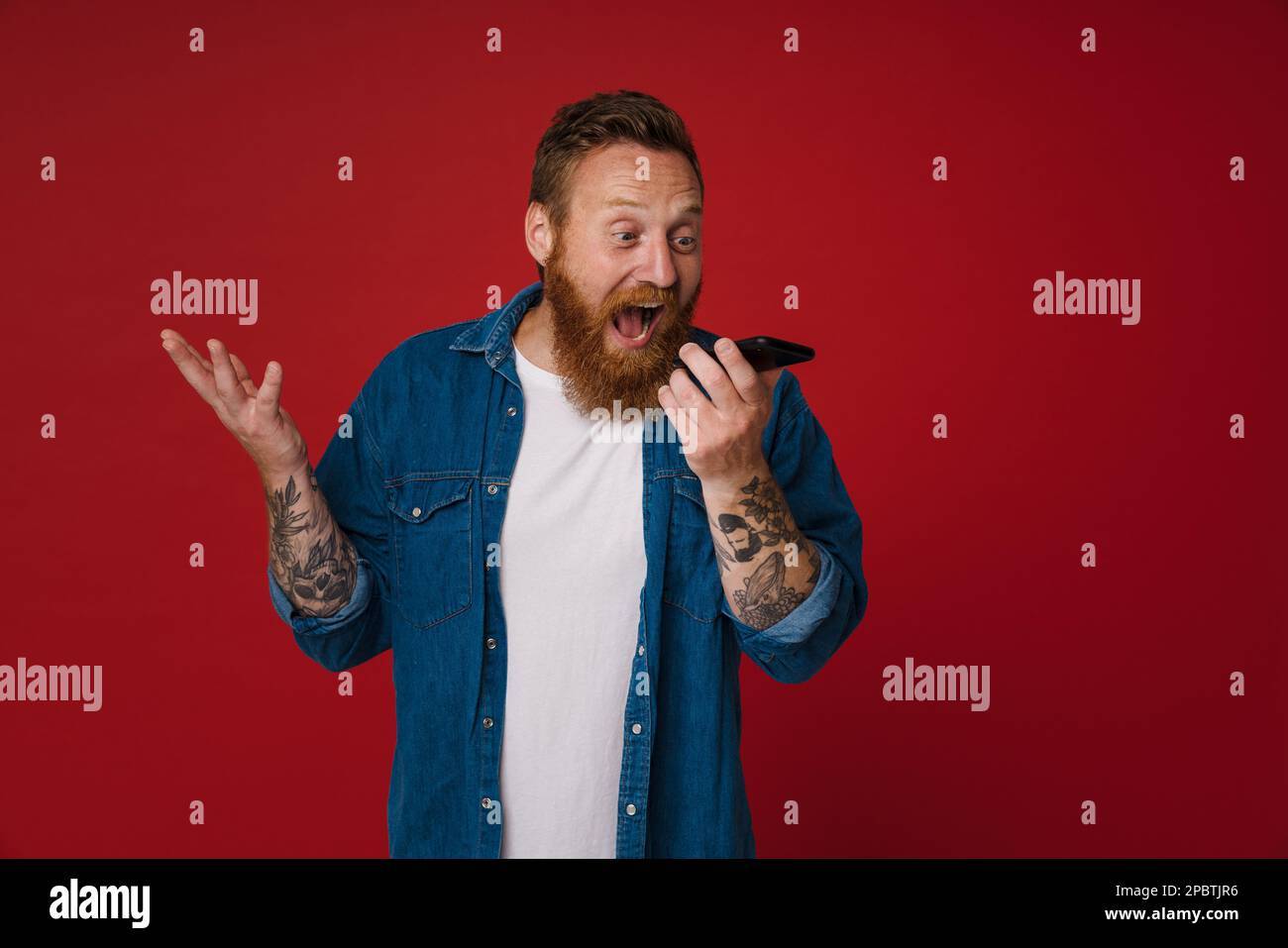 Ginger excited man wearing denim shirt talking on cellphone and ...