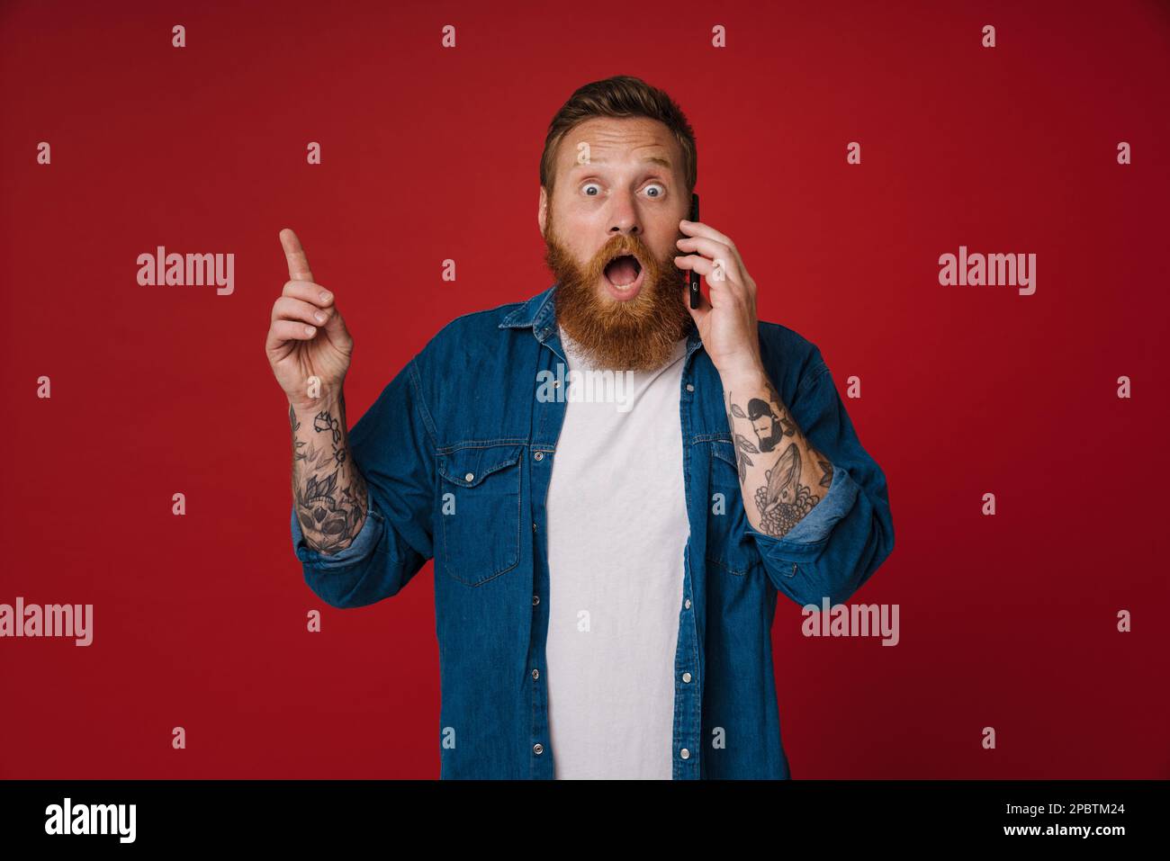 Ginger excited man wearing denim shirt talking on cellphone and ...