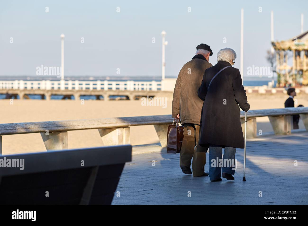 Elderly couple walking along the promenade at the beach Stock Photo - Alamy