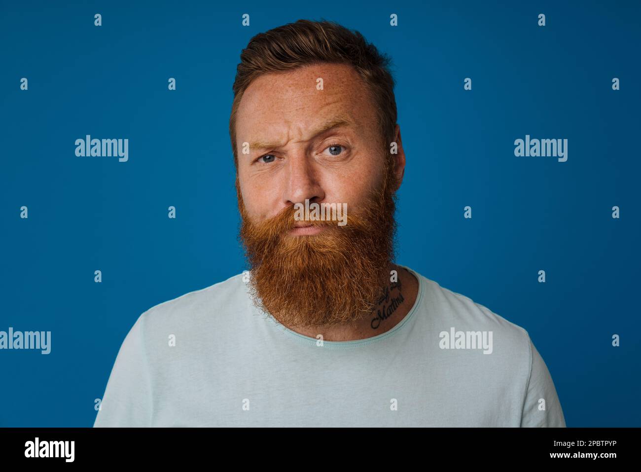 Ginger puzzled man with beard frowning and looking at camera isolated ...