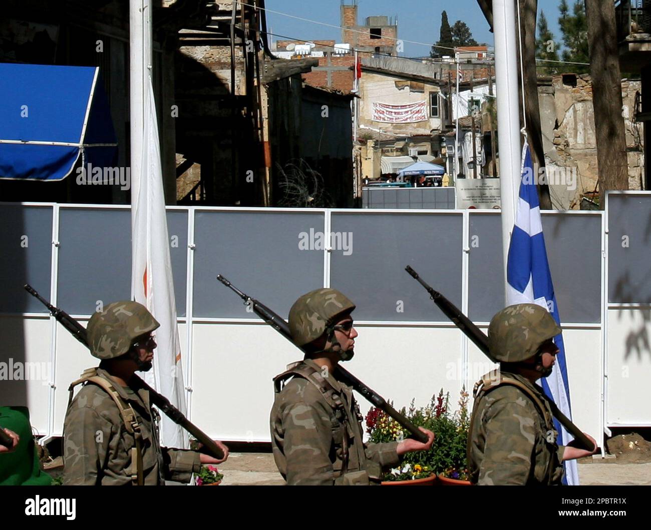 Cypriot soldiers stand with their guns in front of a temporary barrier ...
