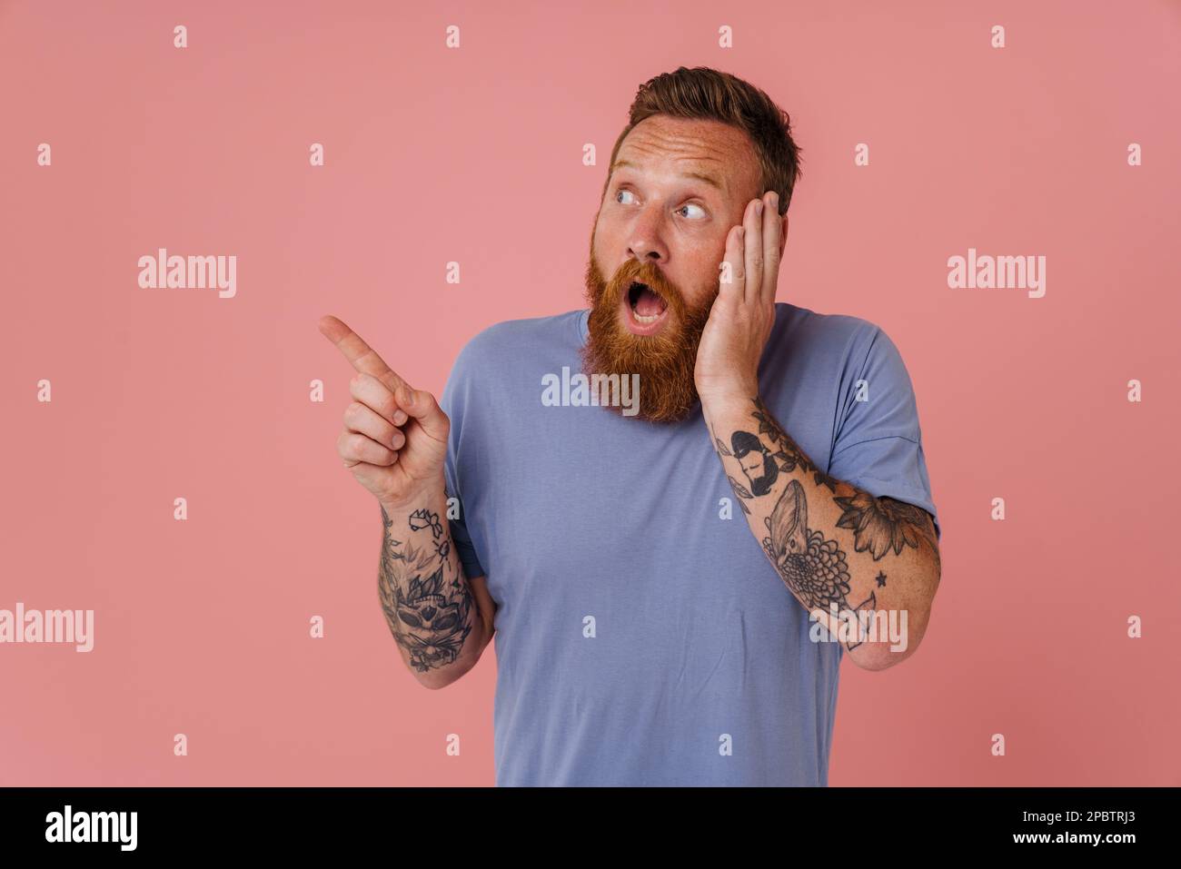 Ginger shocked man with beard screaming and pointing finger side ...