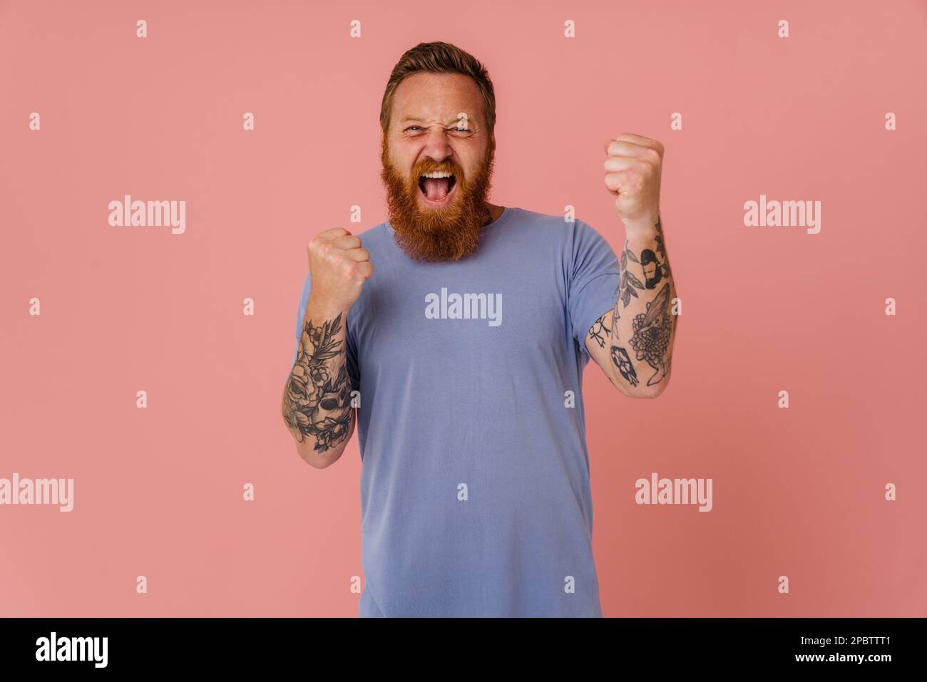 Ginger white man screaming and making winner gesture isolated over pink ...