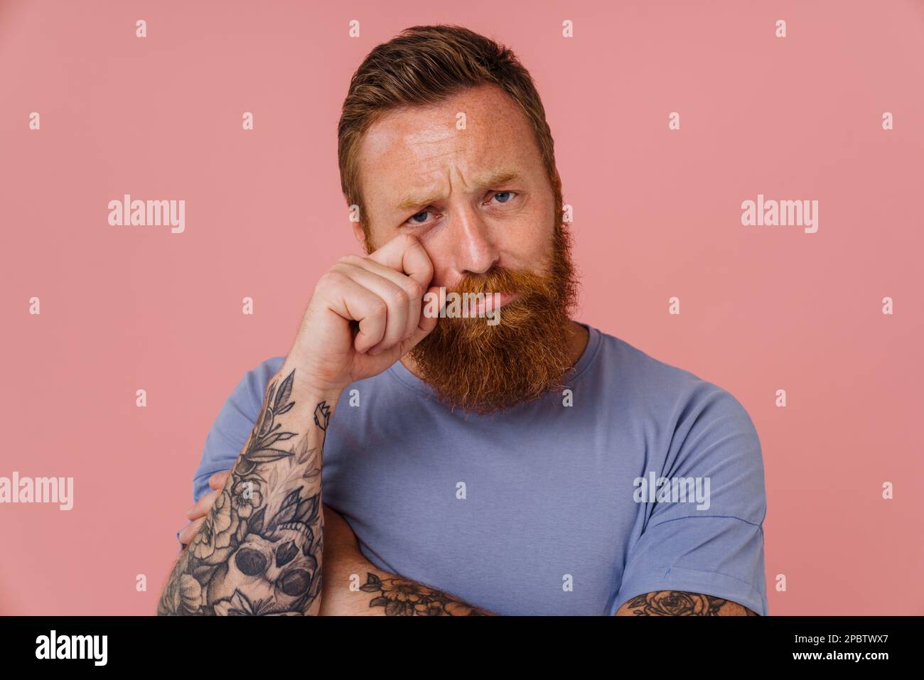Ginger sad man with beard crying while wiping his tears isolated over ...