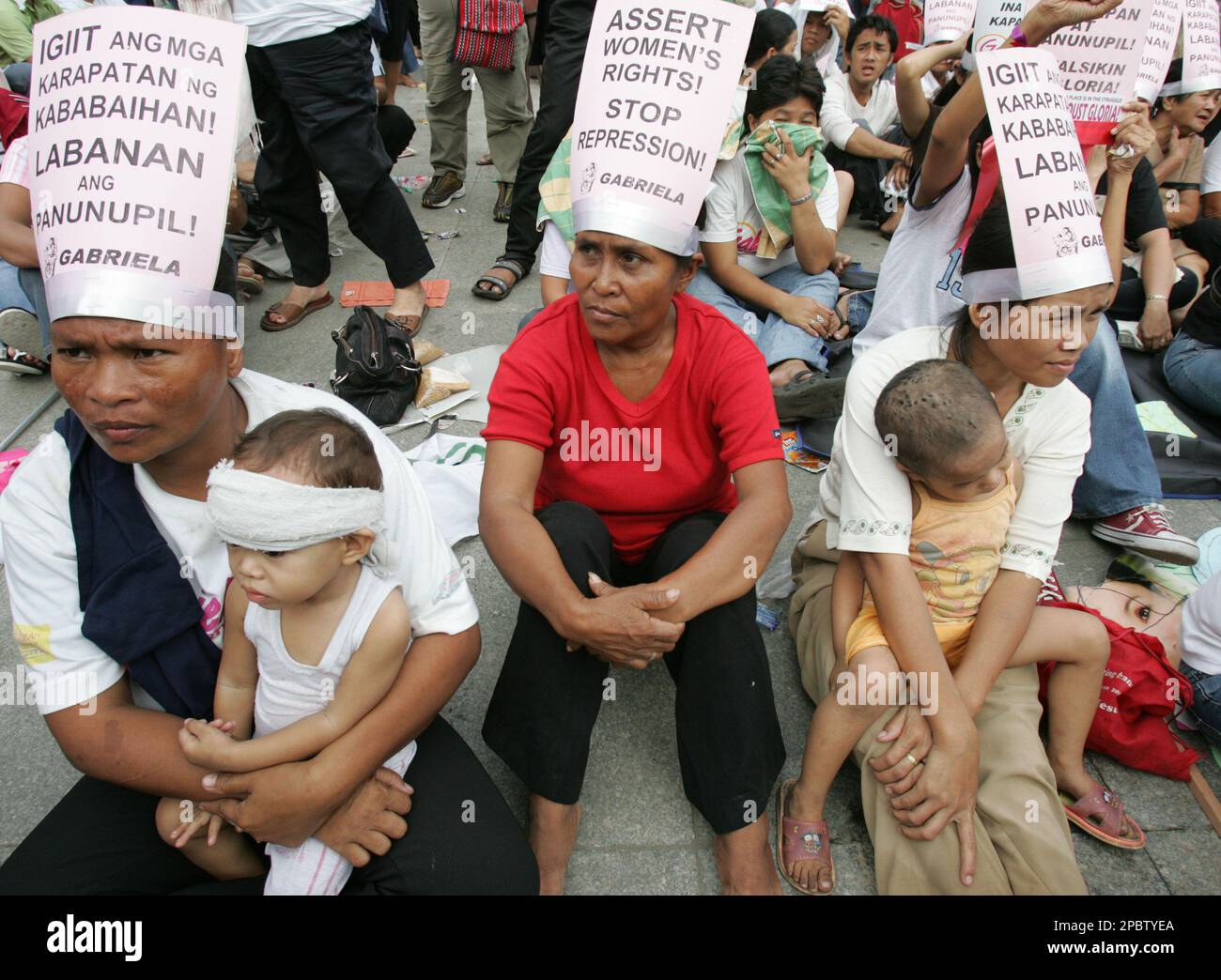 Filipino women protesters, cuddling their children, wear chef's hats ...