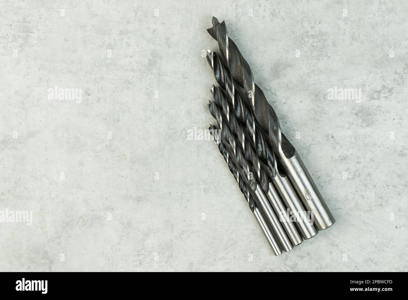 Stainless steel cordless drill heads on the gray background, wooden ...