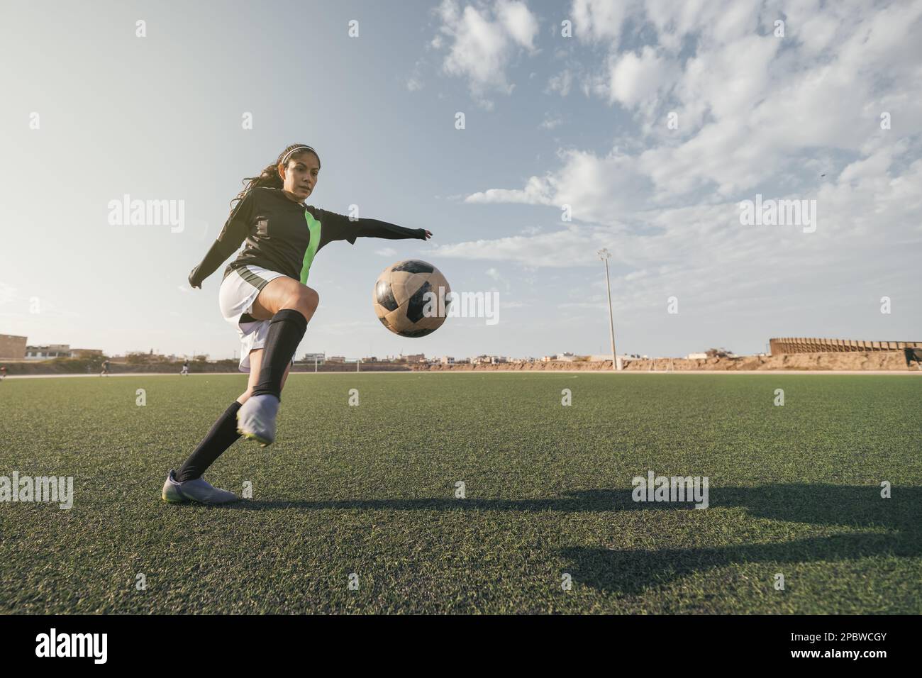 Young female soccer player kicking ball in a stadium Stock Photo - Alamy