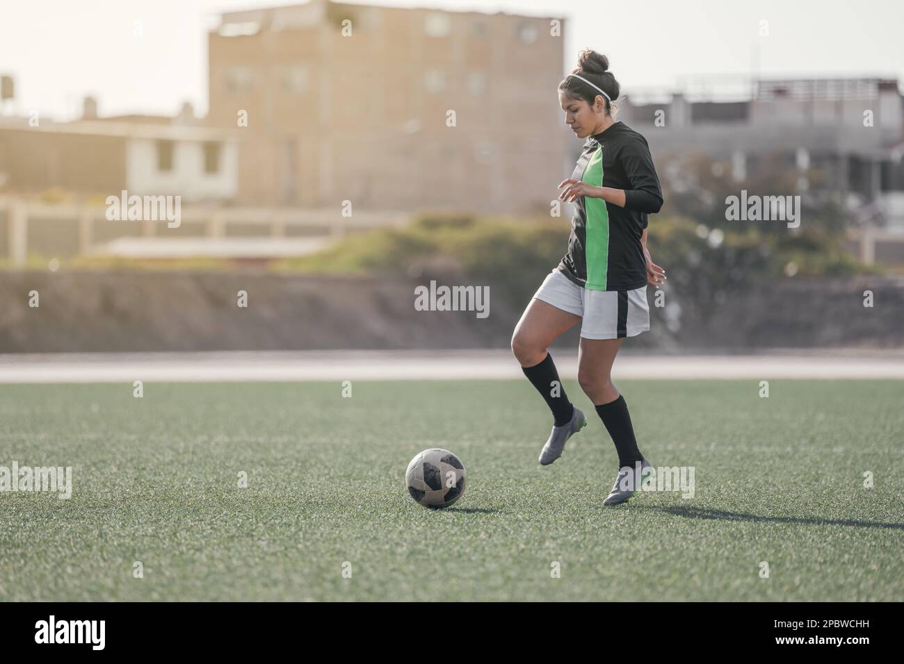 Young female soccer player kicking ball in a stadium Stock Photo - Alamy