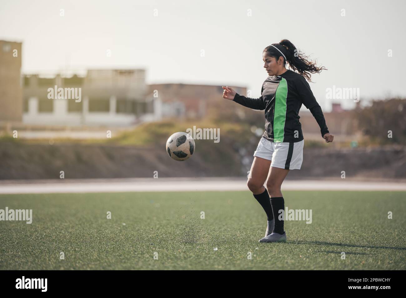 Young female soccer player kicking ball in a stadium Stock Photo - Alamy