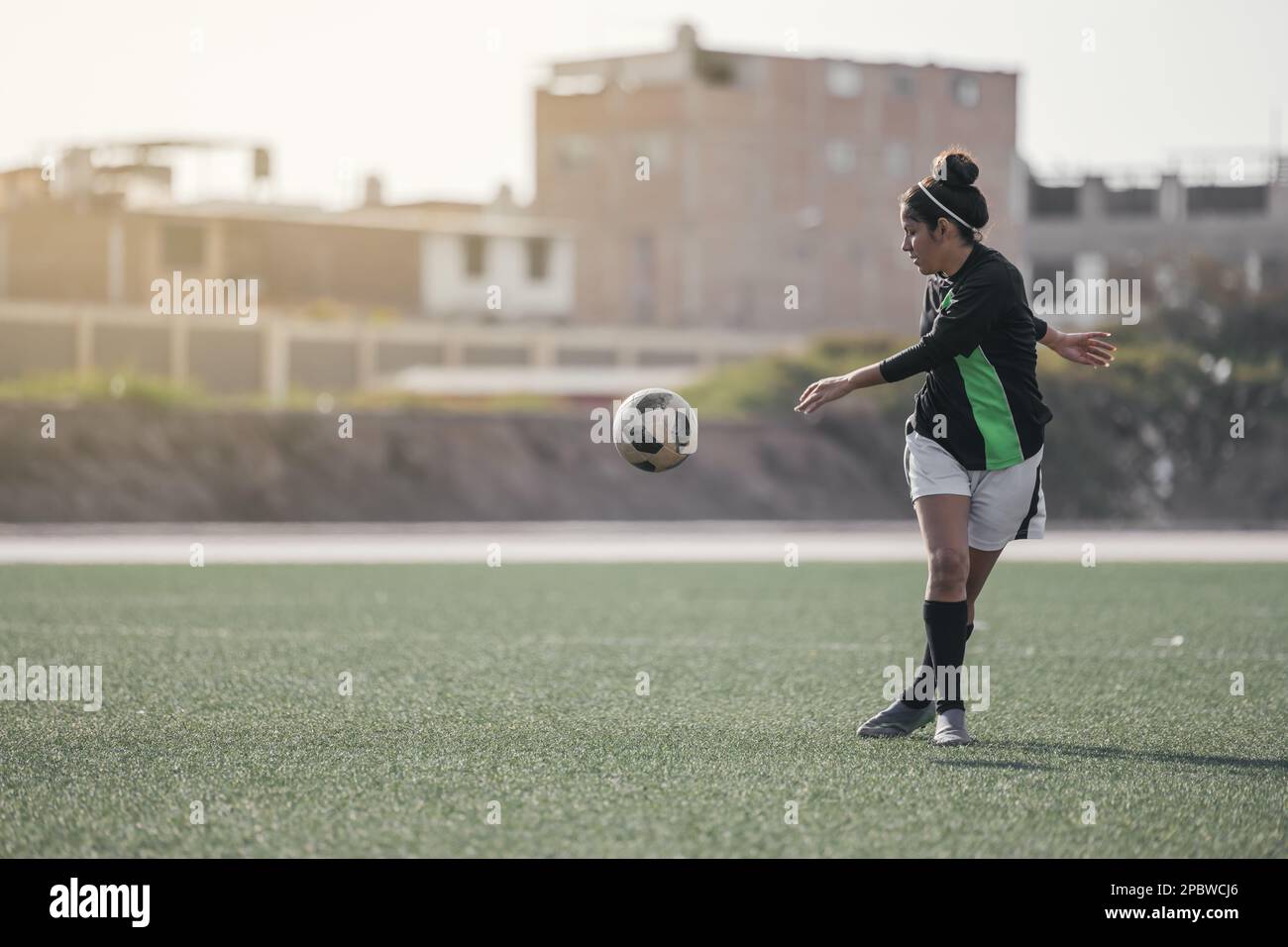 Young female soccer player kicking ball in a stadium Stock Photo - Alamy