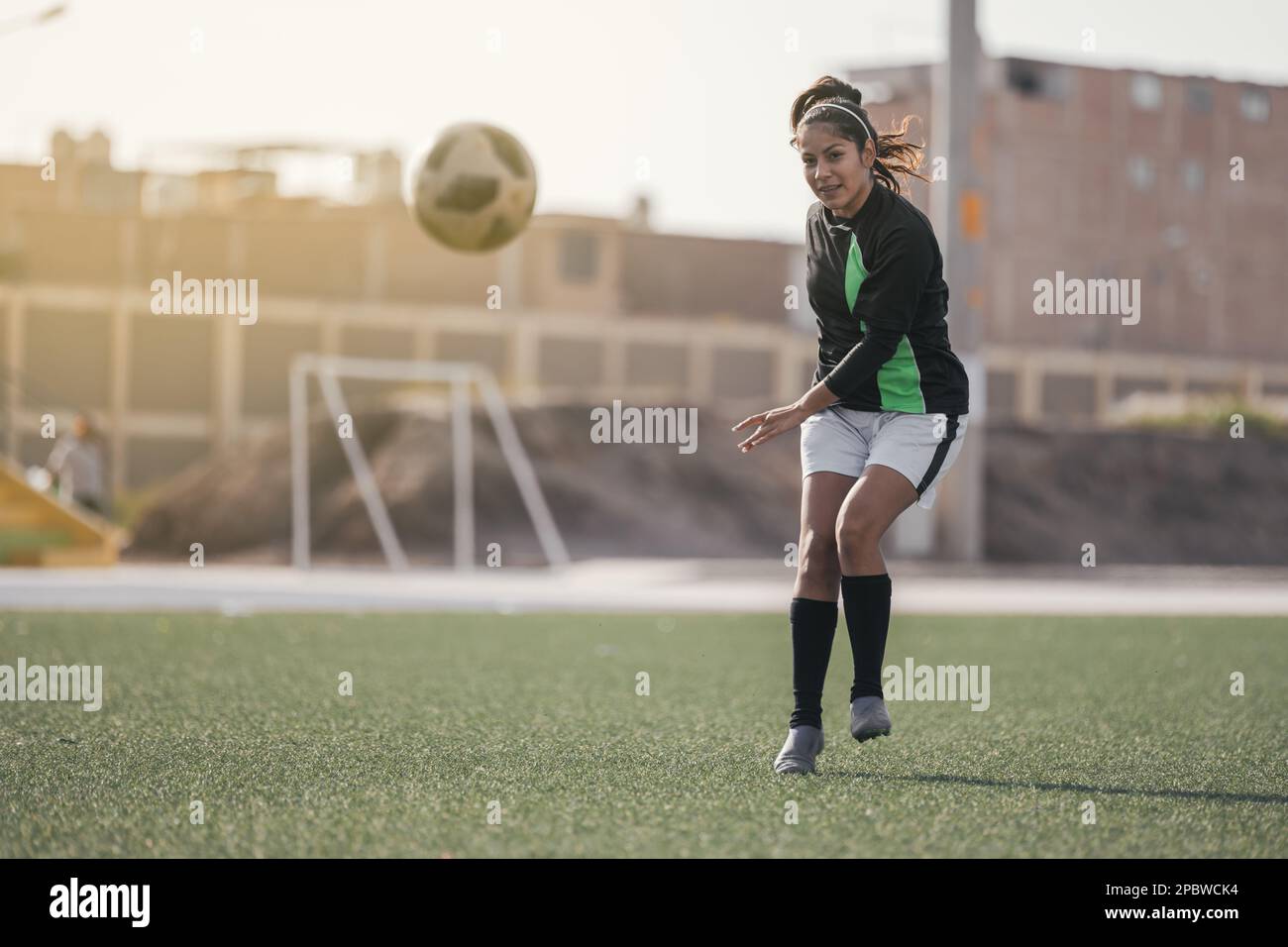 Young female soccer player kicking ball in a stadium Stock Photo - Alamy