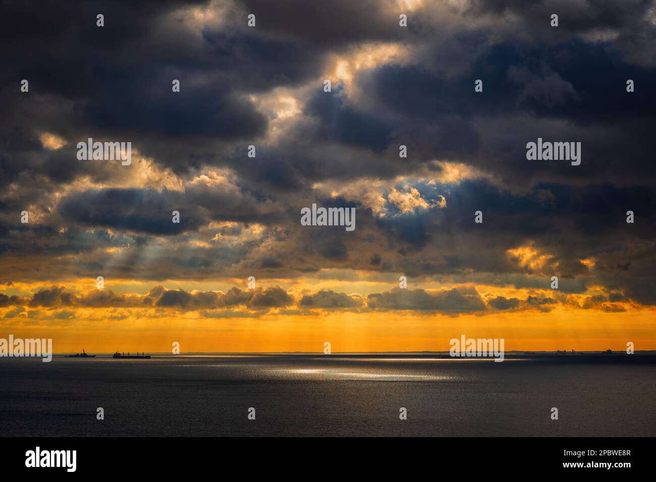 Cloudscape over the Baltic Sea with sun shining through rain clouds and ...