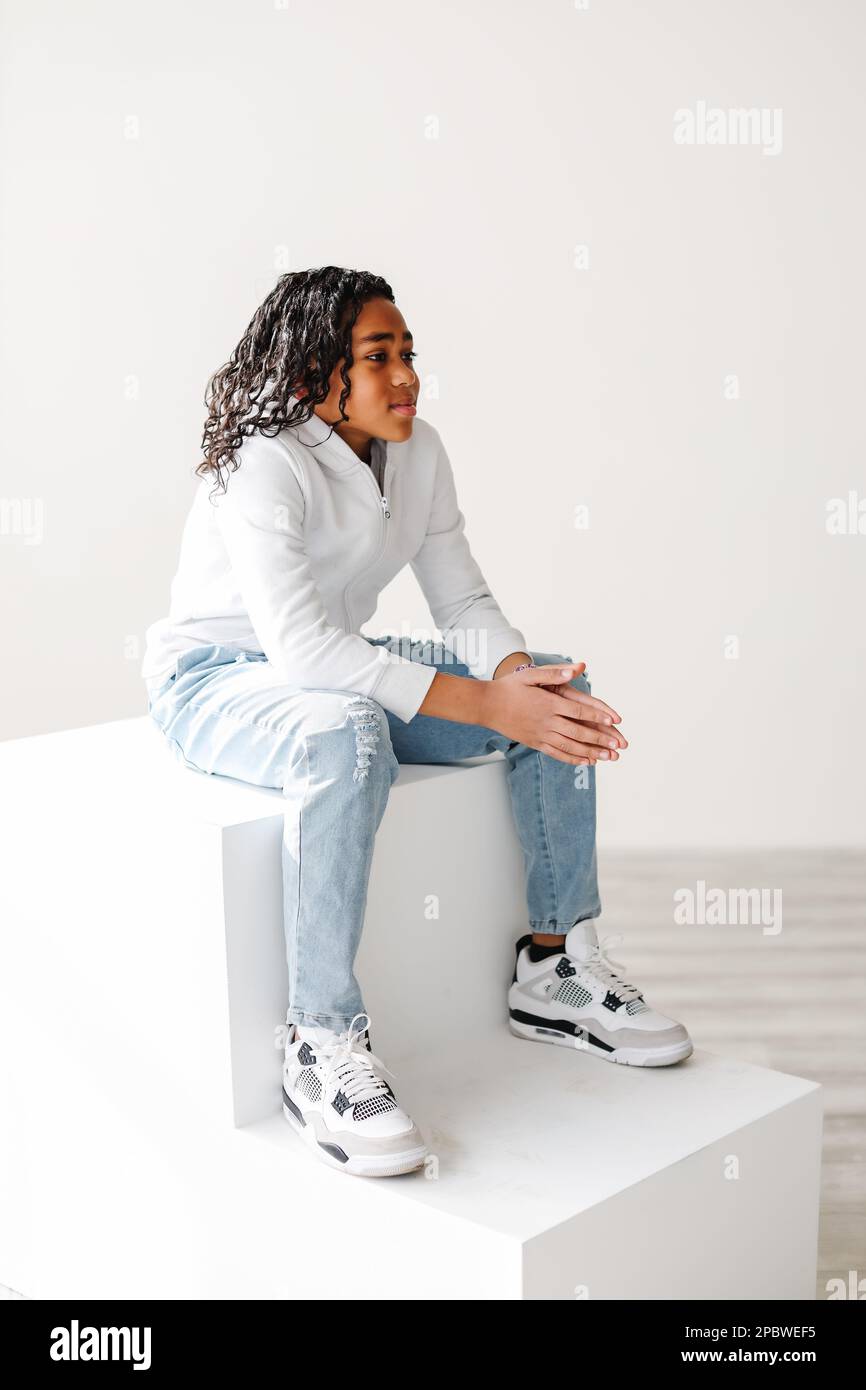 Mixed-race brown boy with long curly hair sitting inside on steps Stock ...
