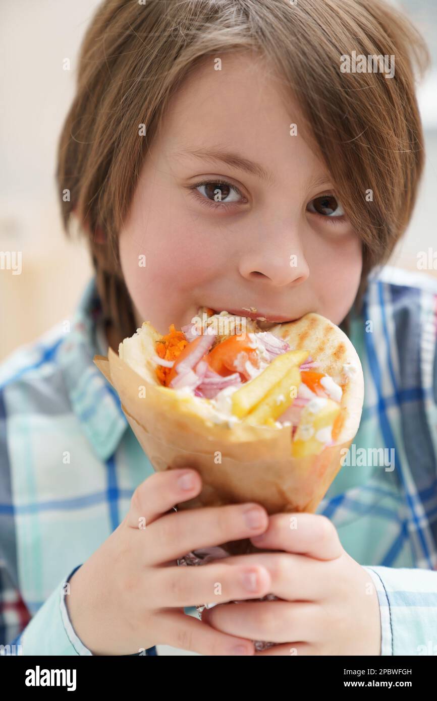 Potrait of hungry little boy biting gyros. Cute elementary age kid ...
