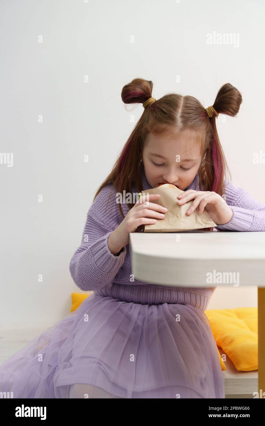 Starving little girl eating pita souvlaki in Greek fast food restaurant ...