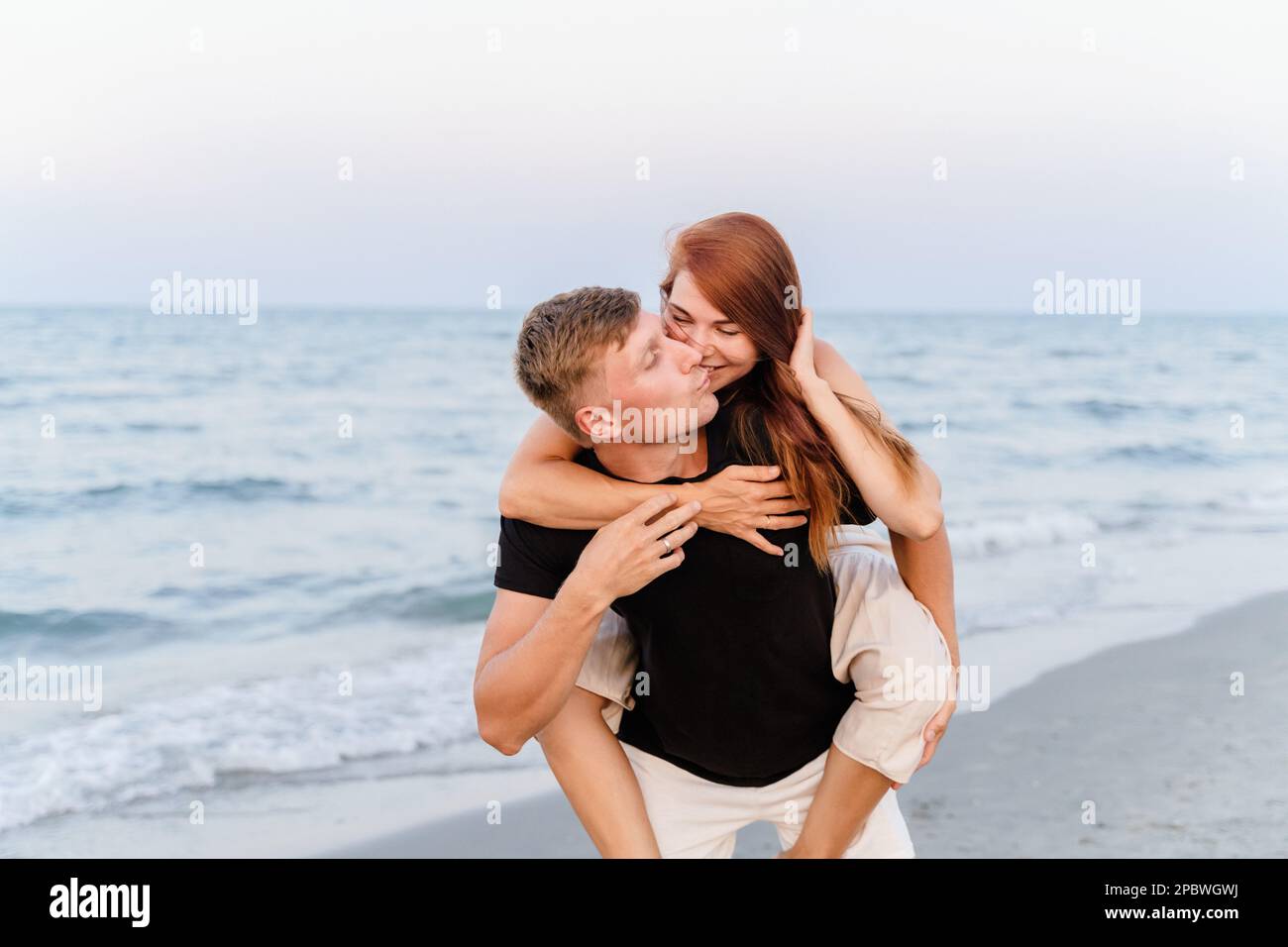 Happy lovers are having fun and fooling around near the sea on beach ...