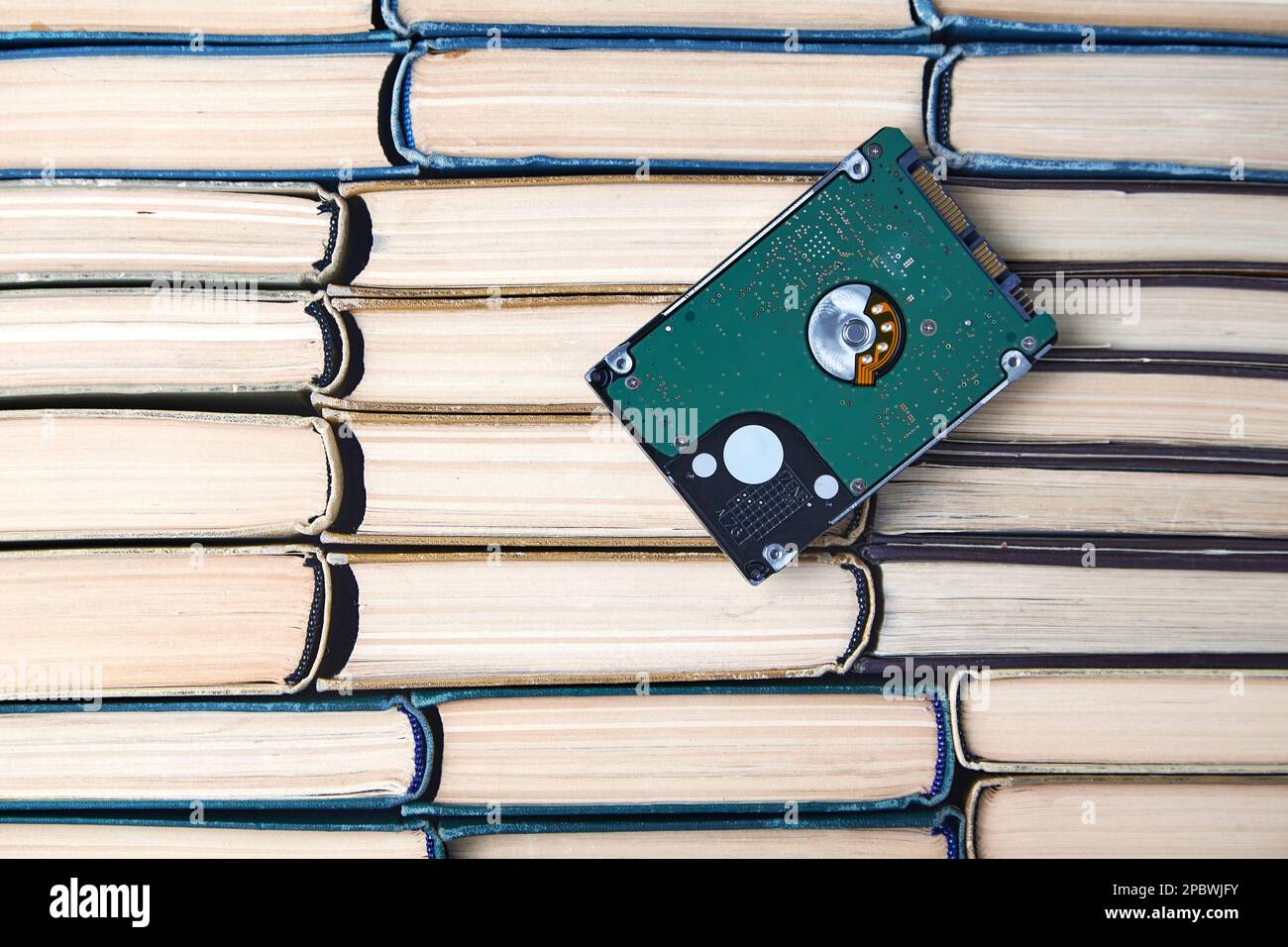 Computer hard drive on the background of a stack of old paper books ...