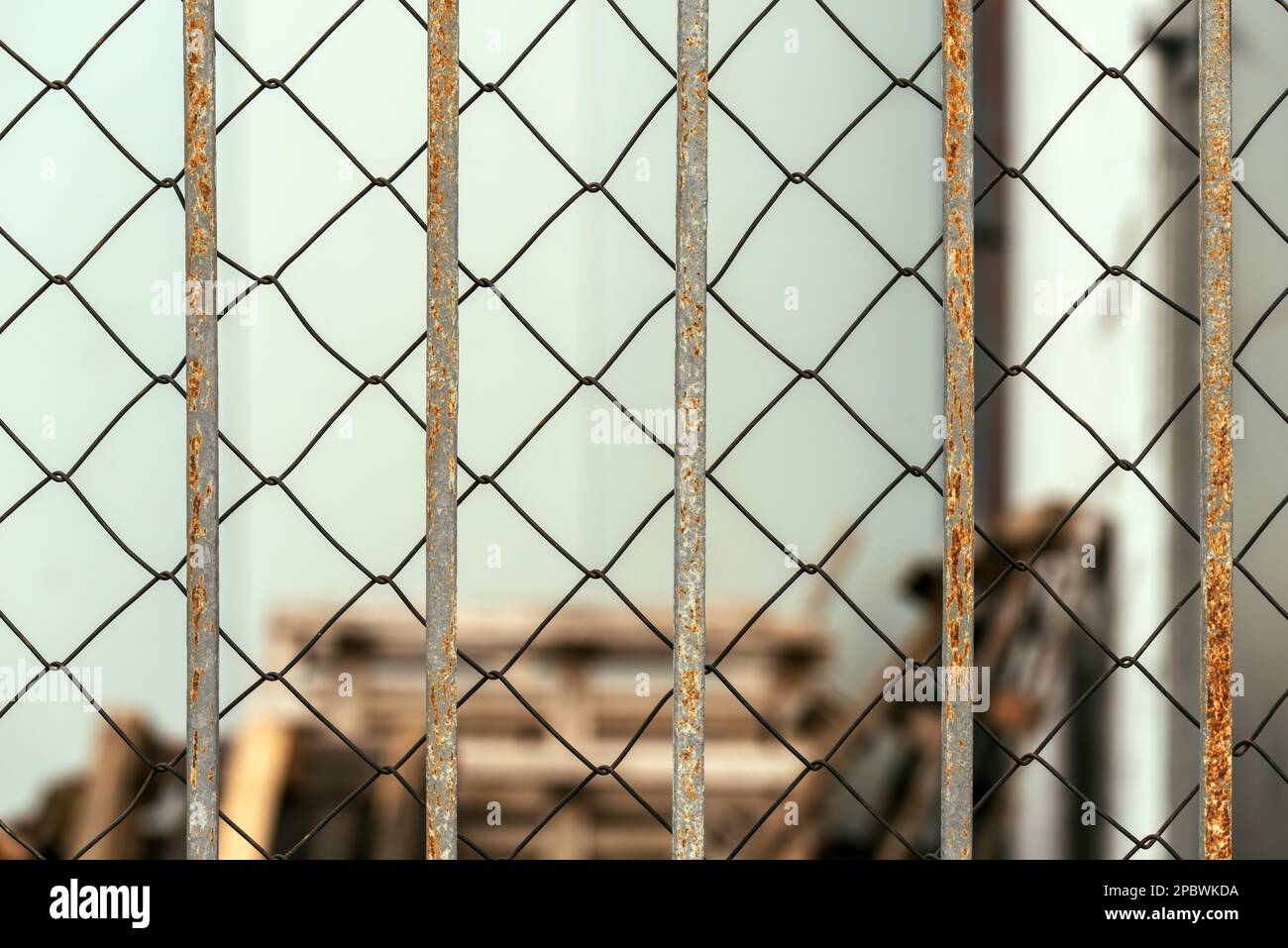 Chain link diamond pattern wire fence and worn metallic bars as ...