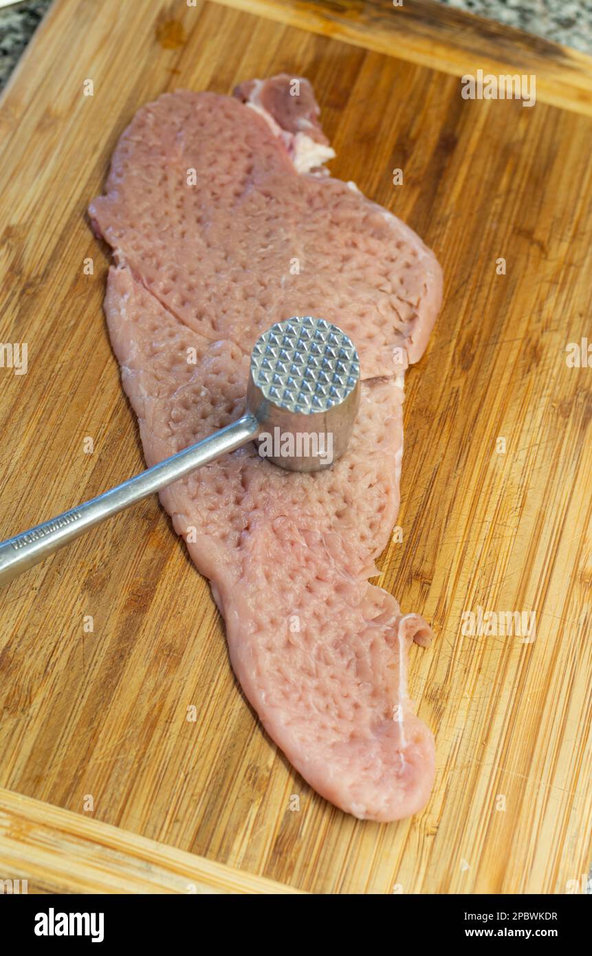 Beater raw piece of Schnitzel meat and a metal meat tenderizer mullet ...