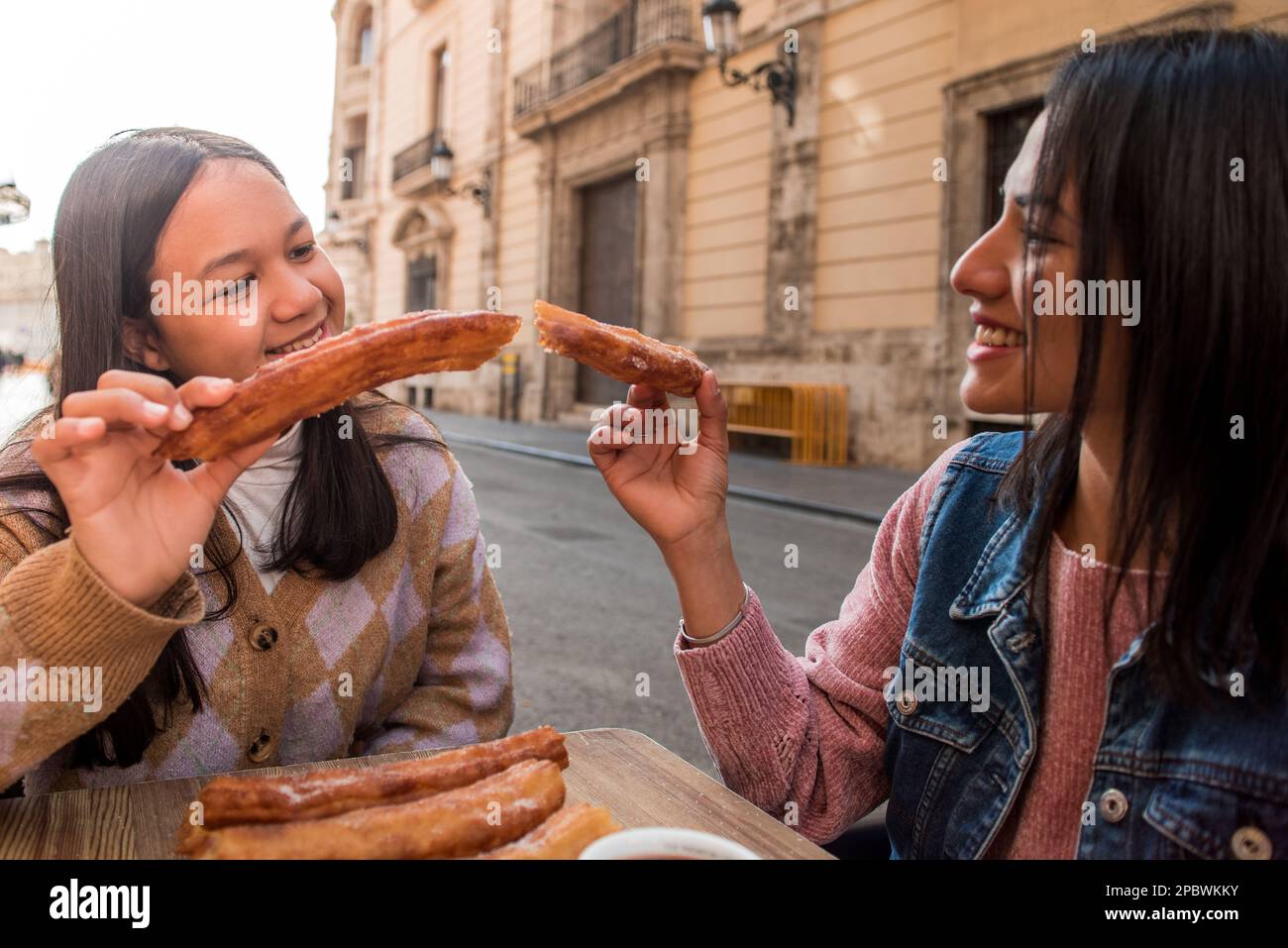 Mother and daughter enjoying time together eating spanish fritters ...