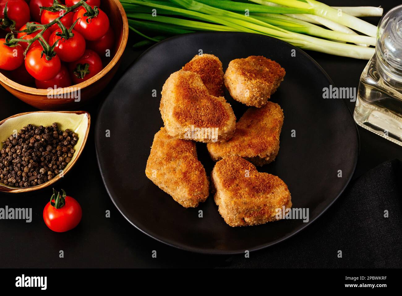 chicken cutlet on a black plate. vegetables and herbs. black bac Stock ...
