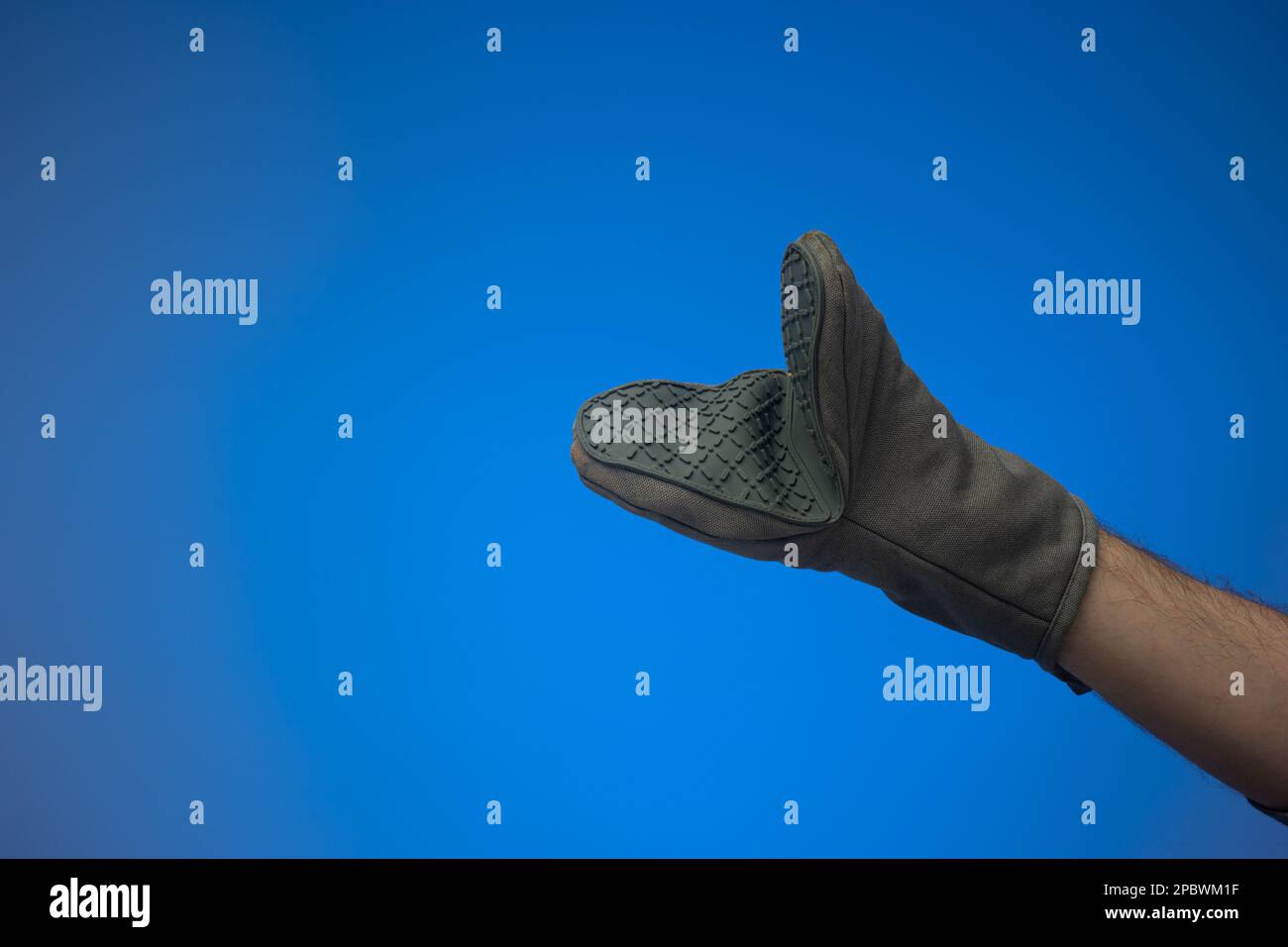 Single gray oven glove or mitten worn by Caucasian male hand. Close up ...