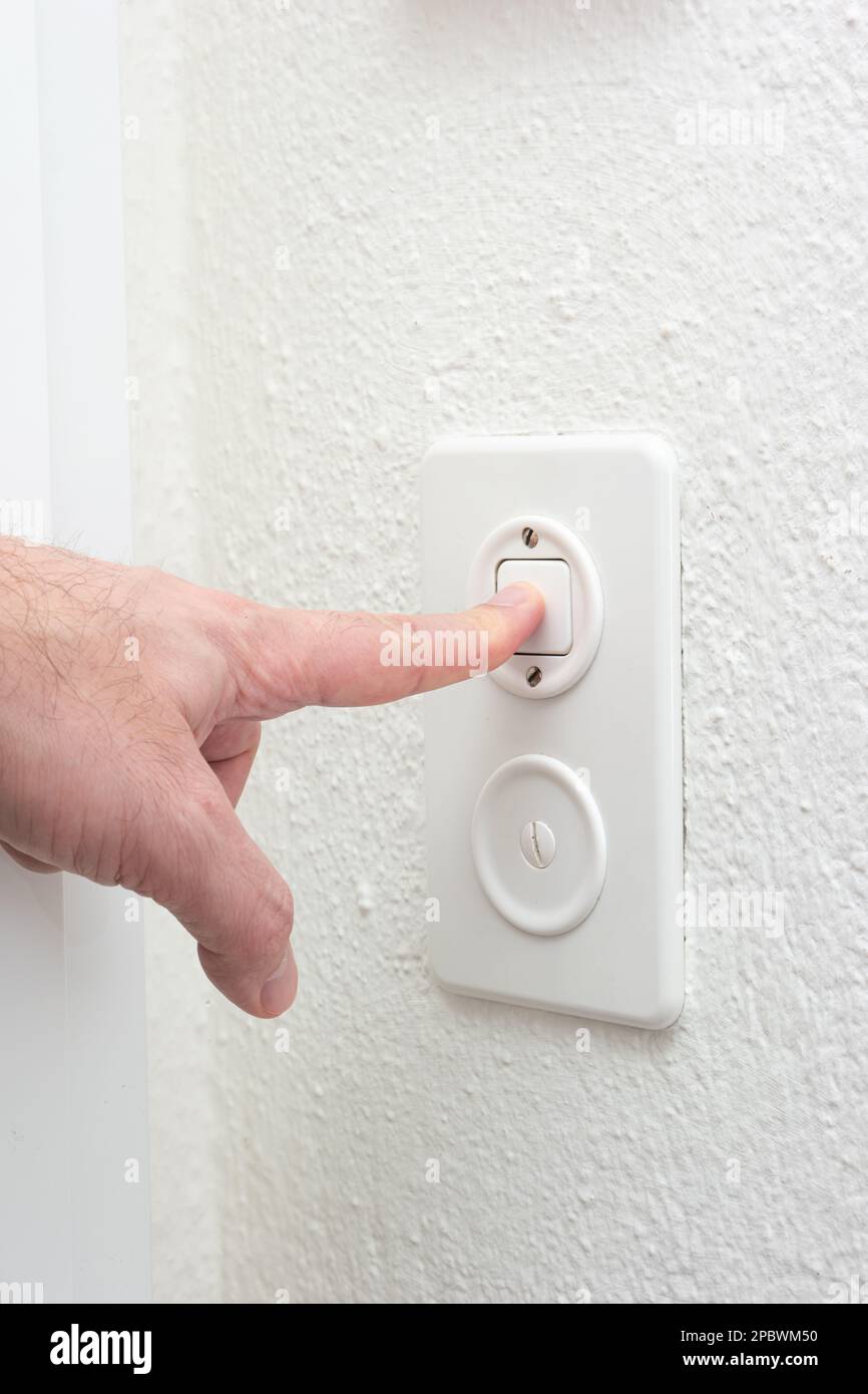 Caucasian male finger pressing the on off light switch inside apartment ...