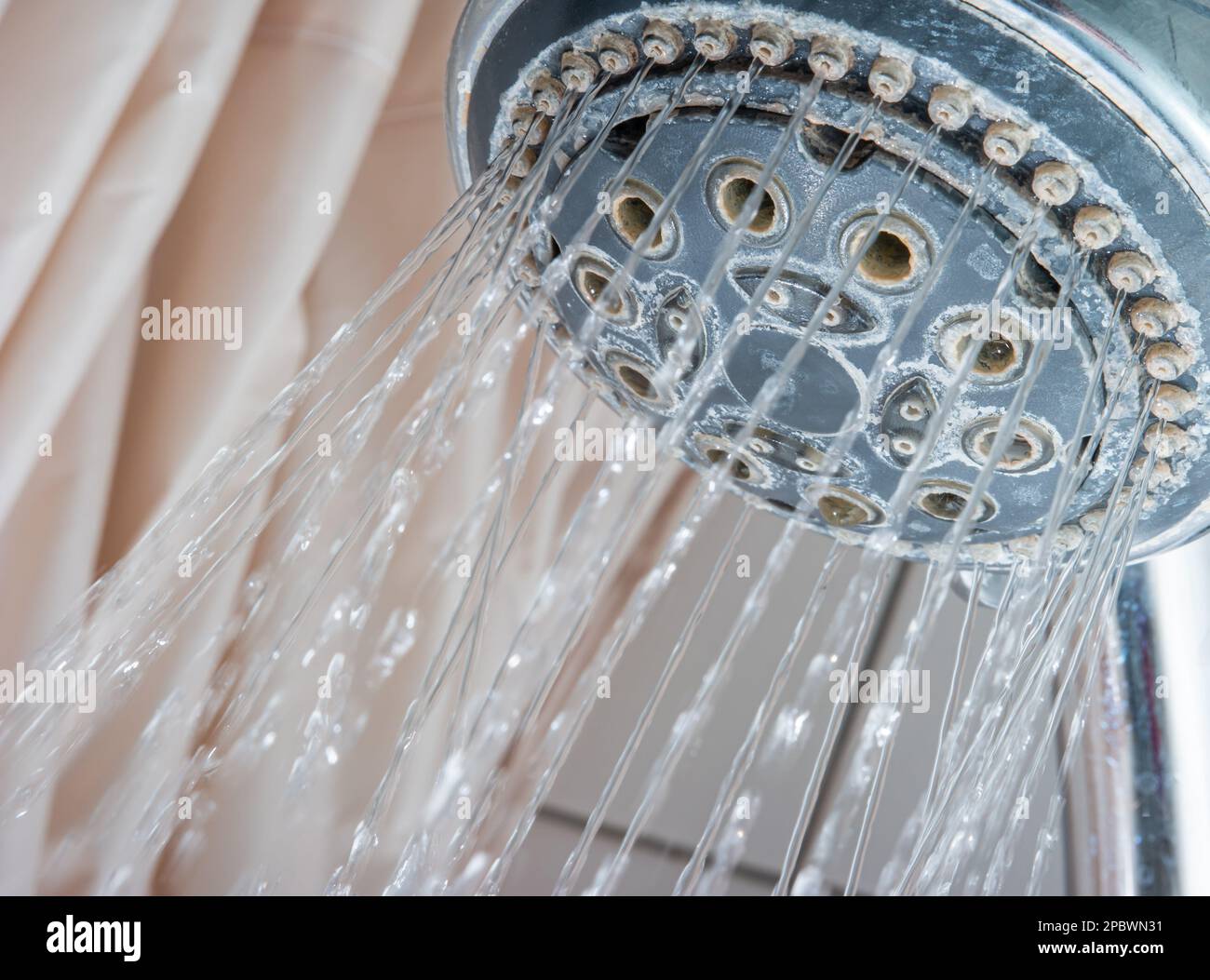 Water streaming out of silver round shower head inside bathroom. Low ...