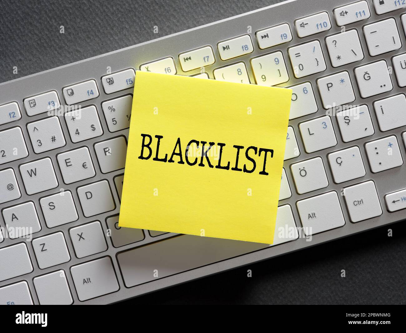 The word blacklist written on a sticky note paper on computer keyboard ...