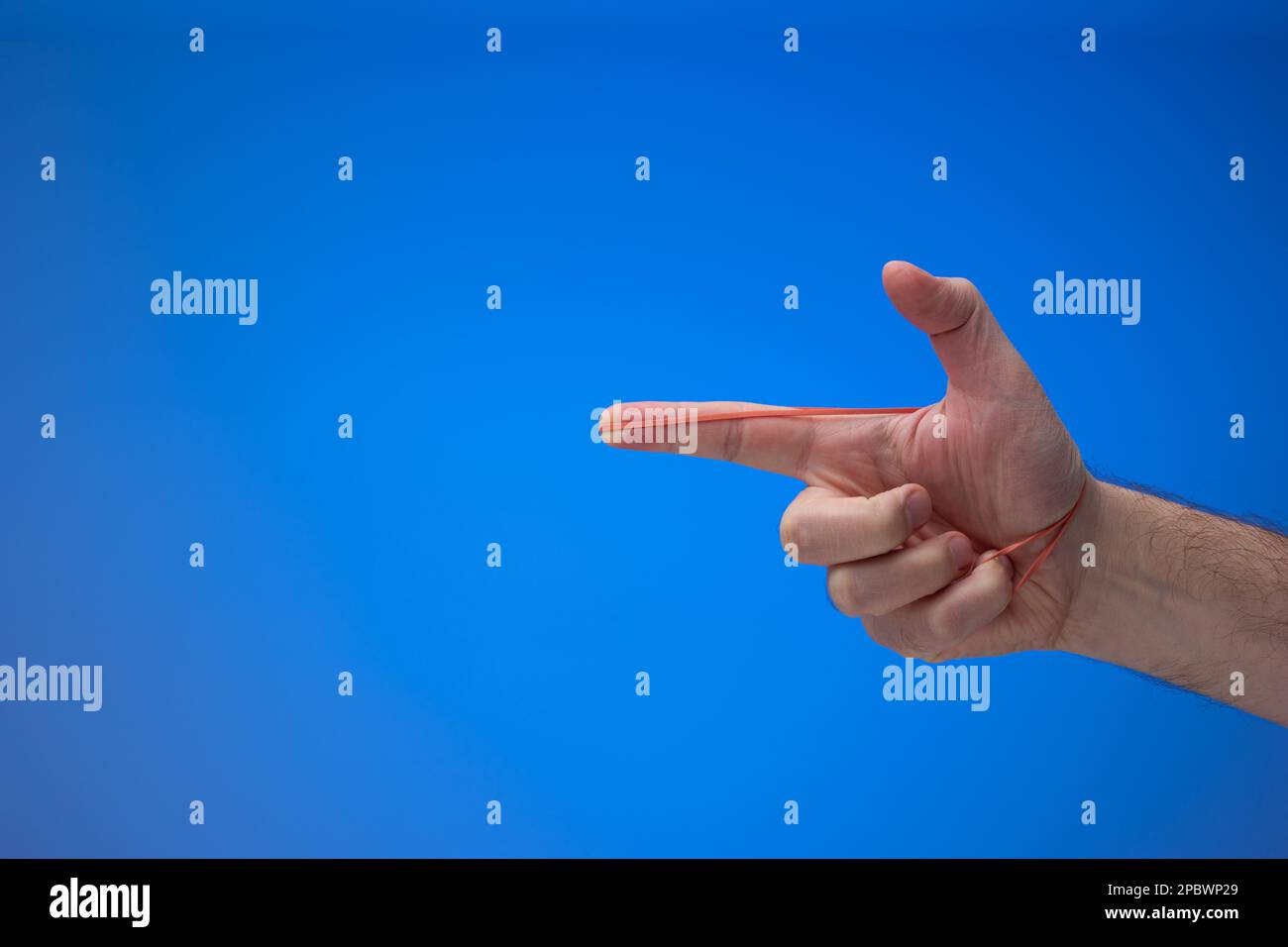 Male hand making a pistol gesture with am elastic rubber band. Close up ...