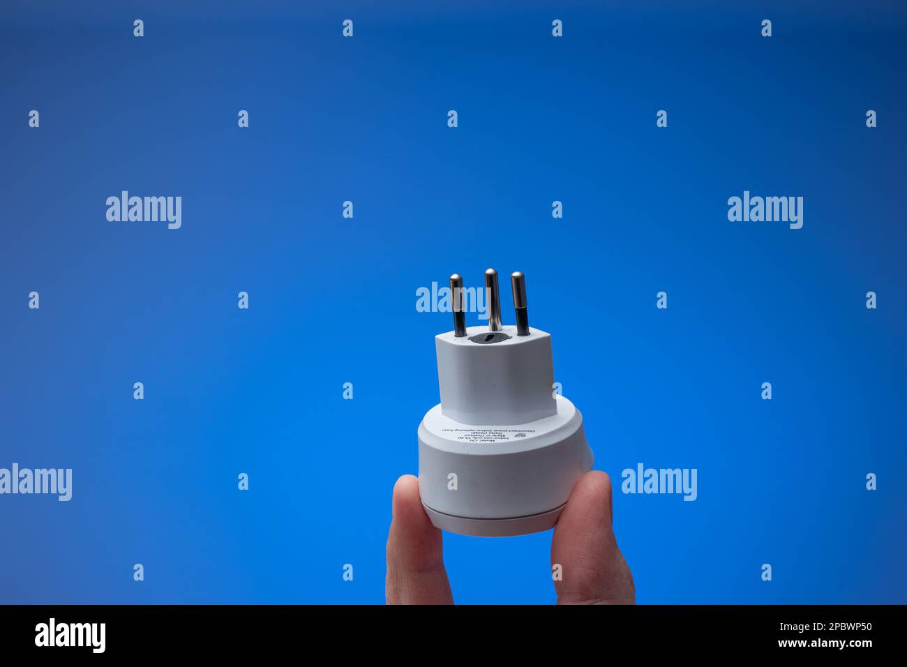 Swiss style electric socket adapter held in hand by male hand. Close up ...